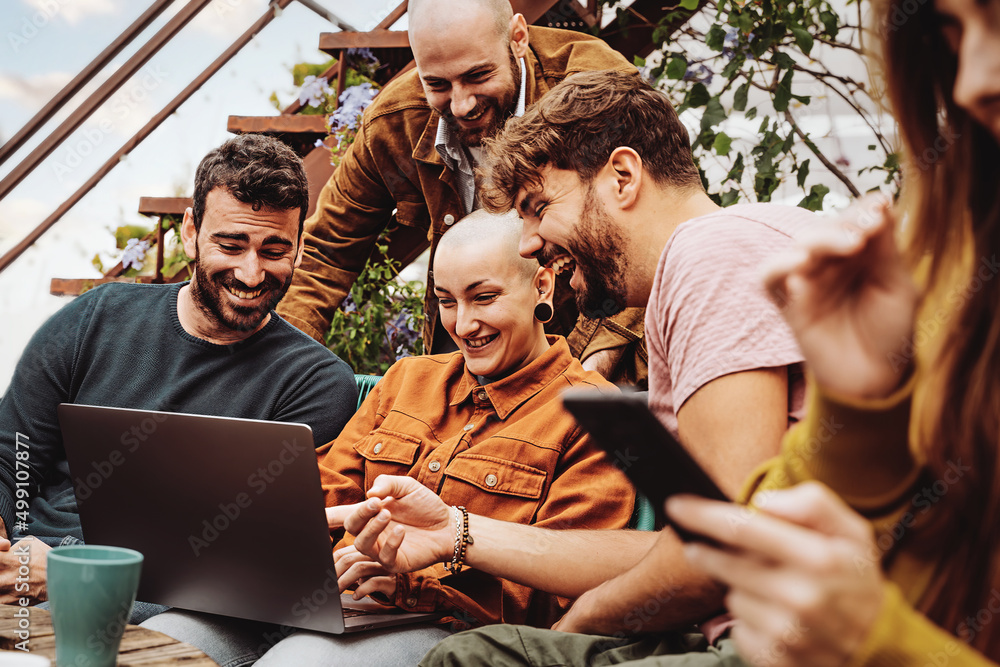 Cheerful group of young people watching internet content with a laptop ...