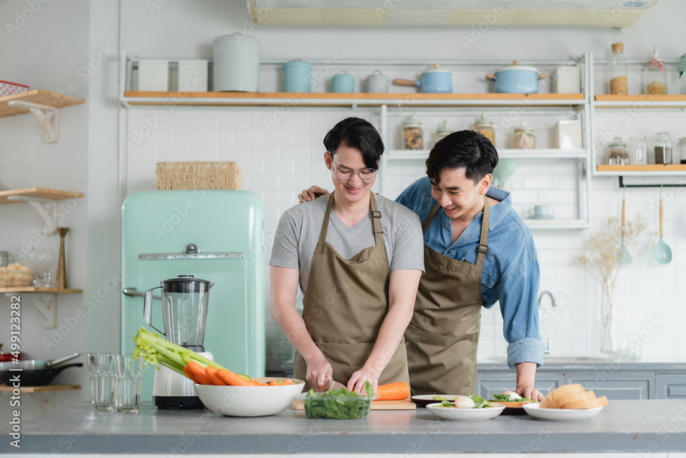 Young gay couple cooking vegetable food together at kitchen in home ...
