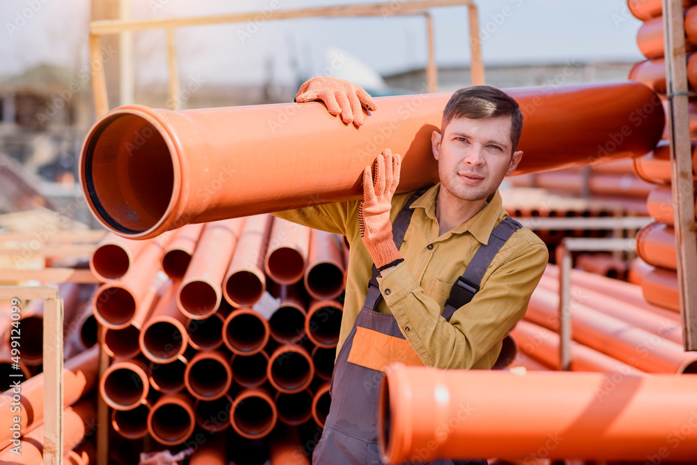 plumber is holding a sewer pipe on his shoulder in a construction pipe ...