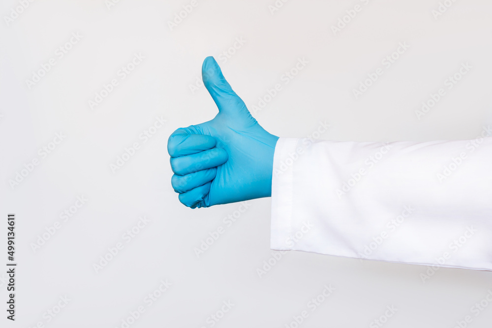 Female doctor hand in a blue glove showing the thumb up gesture ...