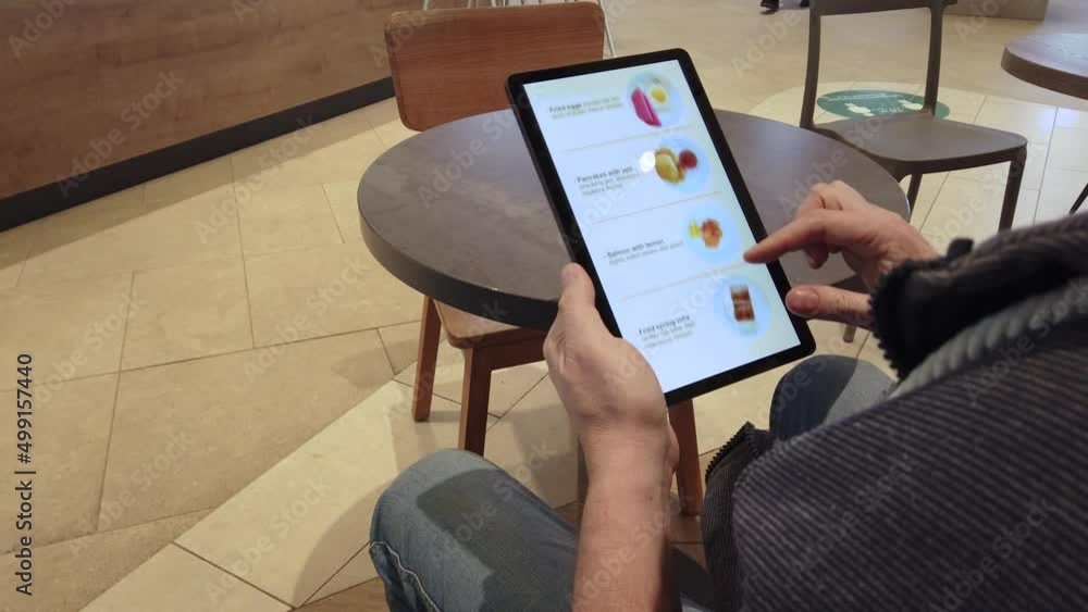 A man sits at a table and looks through the restaurant menu on the ...