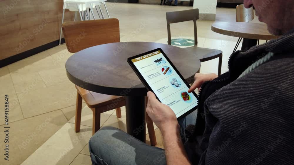 A man sits at a table and looks through the restaurant menu on the ...
