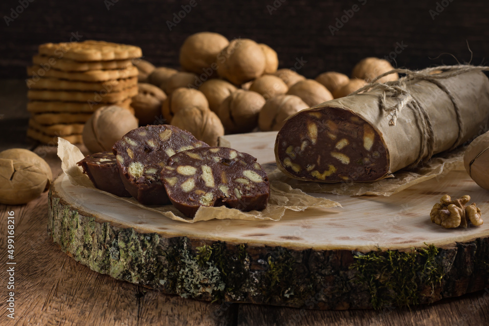 Chocolate salami with nuts displayed on a rustic wooden log ...
