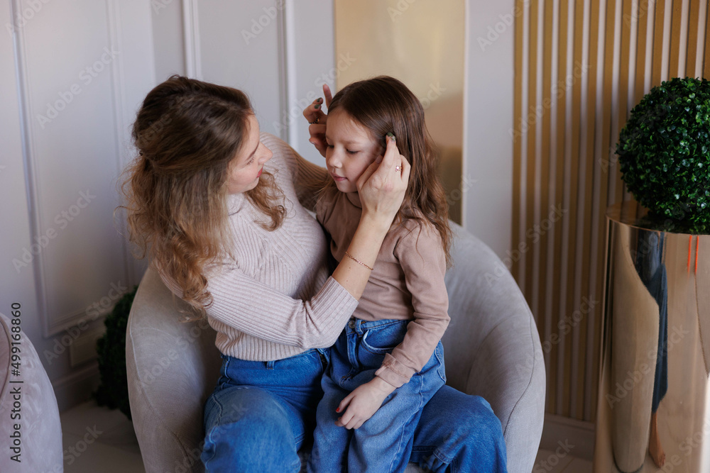 Lovely family mother and daughter embracing and kissing each other indoors. Happy sweet woman ...