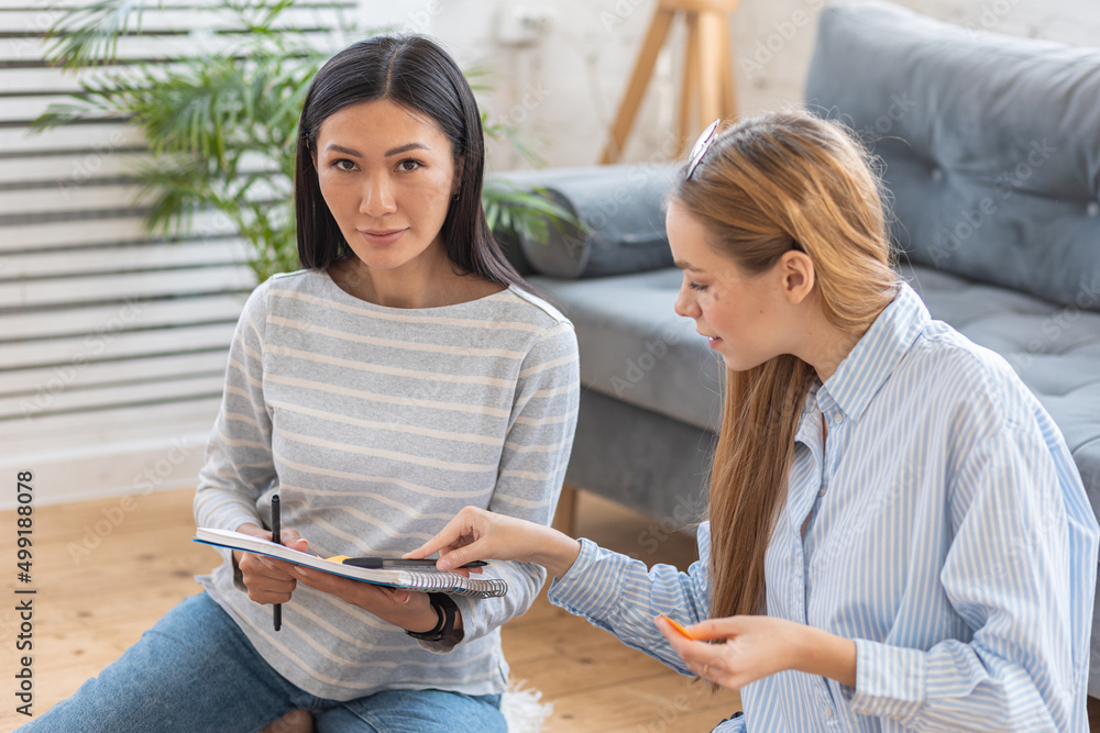 Two young girls learning foreign languages together at home sitting on ...