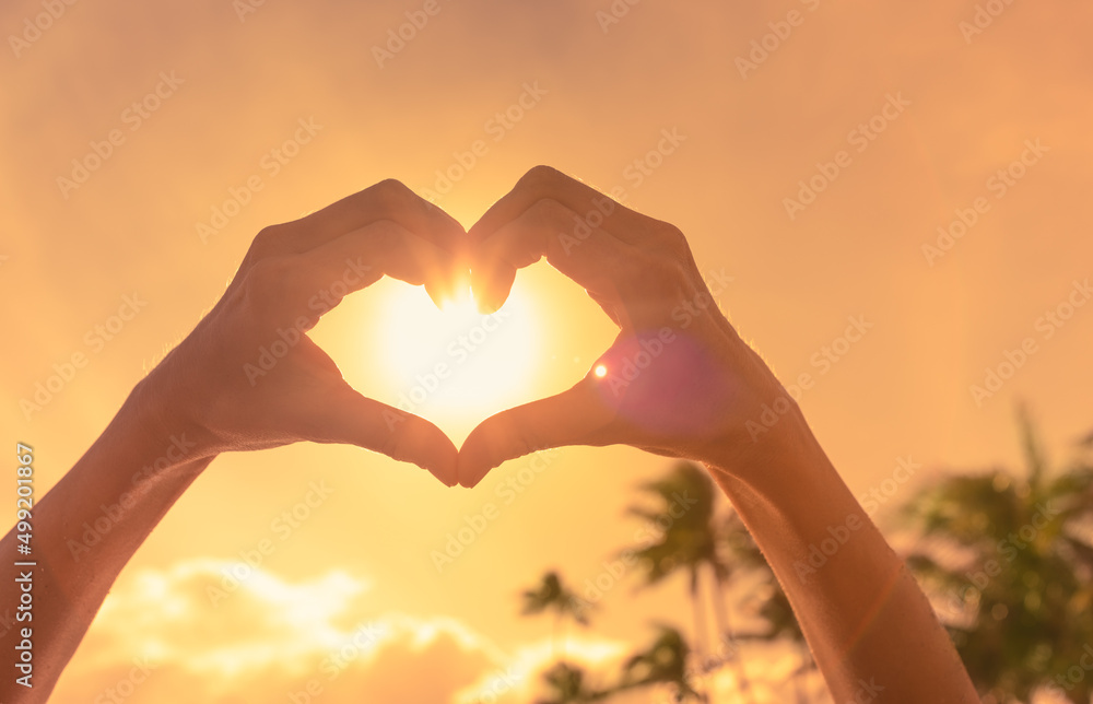 Female making a heart shape on sunset sky. People love, nature symbol ...