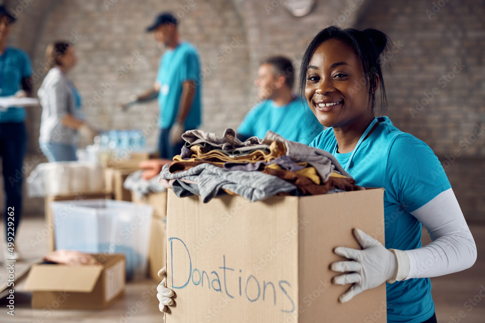 Happy African American woman volunteering at humanitarian aid center ...