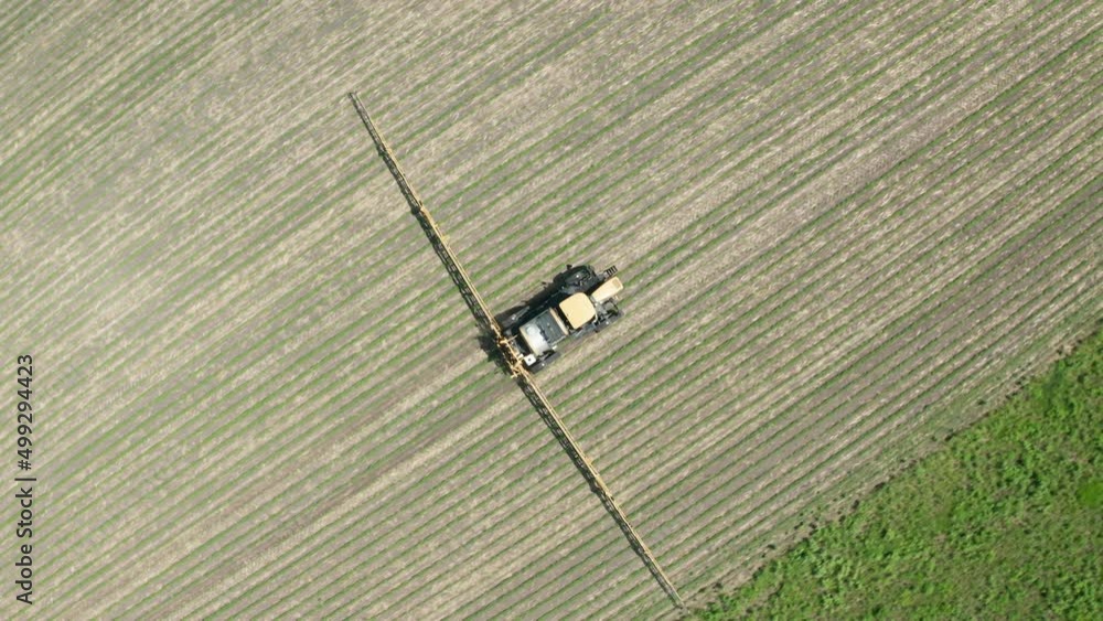 Aerial top down, farm tractor spraying pesticide, herbicide and ...