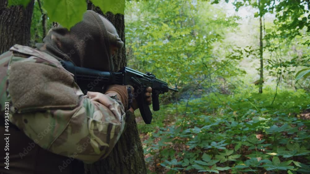 Shot back soldier man in camouflage is aiming with a machine gun ...
