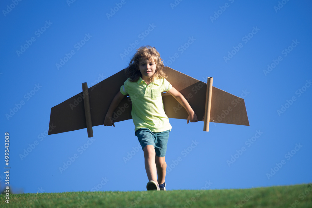 Child boy like a pilot with toy wings against blue sky. Kids freedom ...
