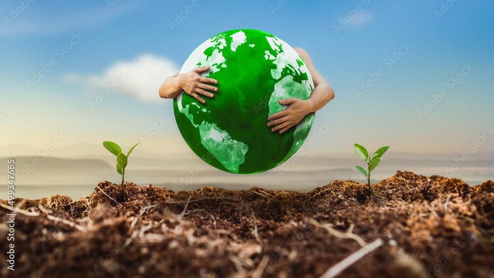 environmental concept on earth day. Hands hugging the green world with ...