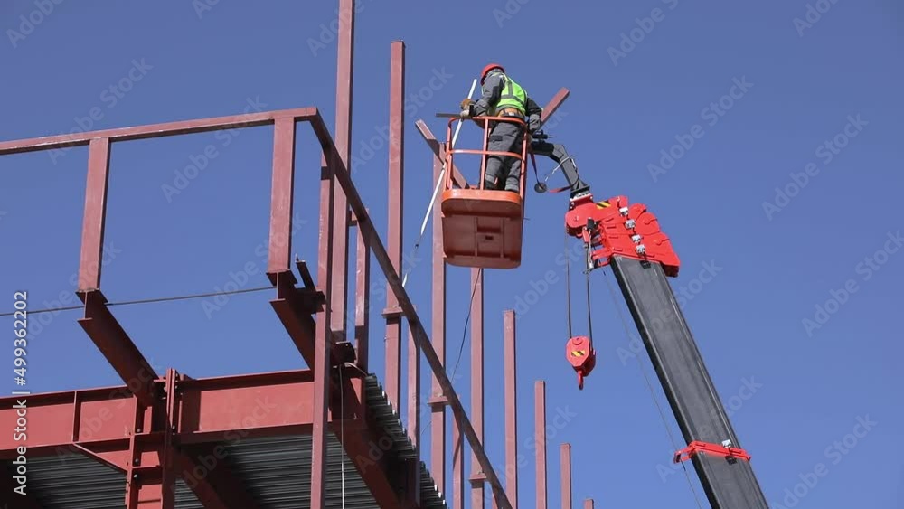 Male builders work at height in a lifting cradle, creating the iron ...