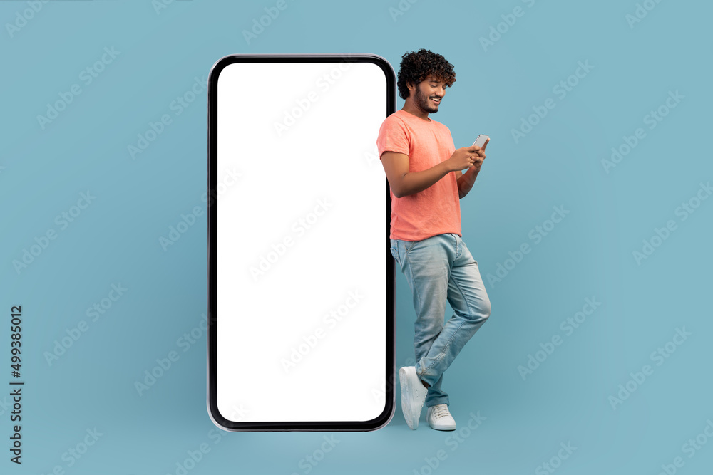 Cool indian guy leaning on huge smartphone, using cell phone Stock ...