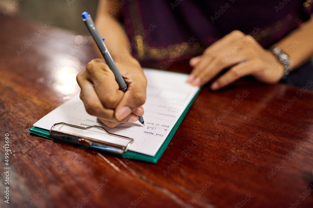Time to check in. Closeup shot of a woman filling out a hotel check-in ...