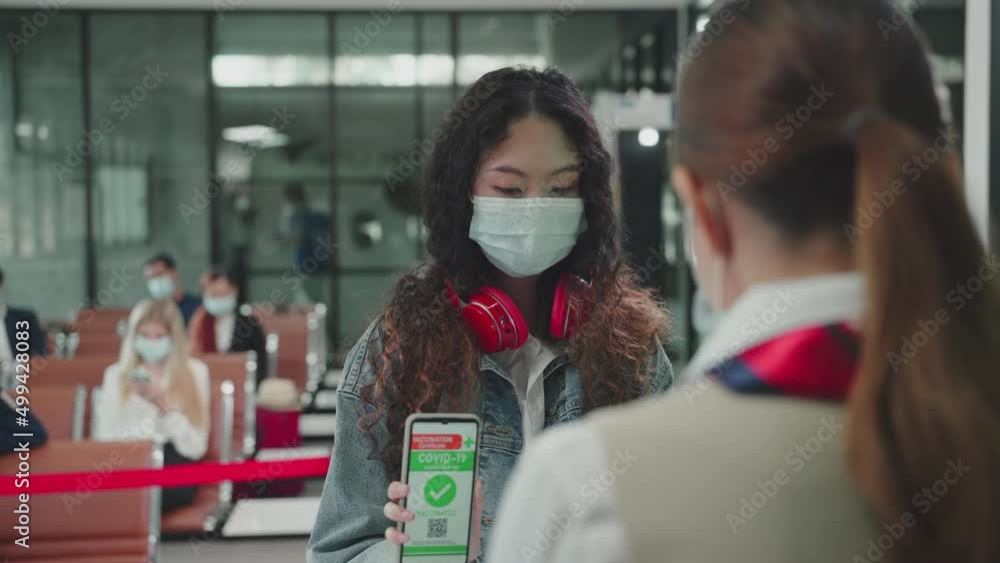 Asian woman wearing face mask showing vaccine information on smartphone ...