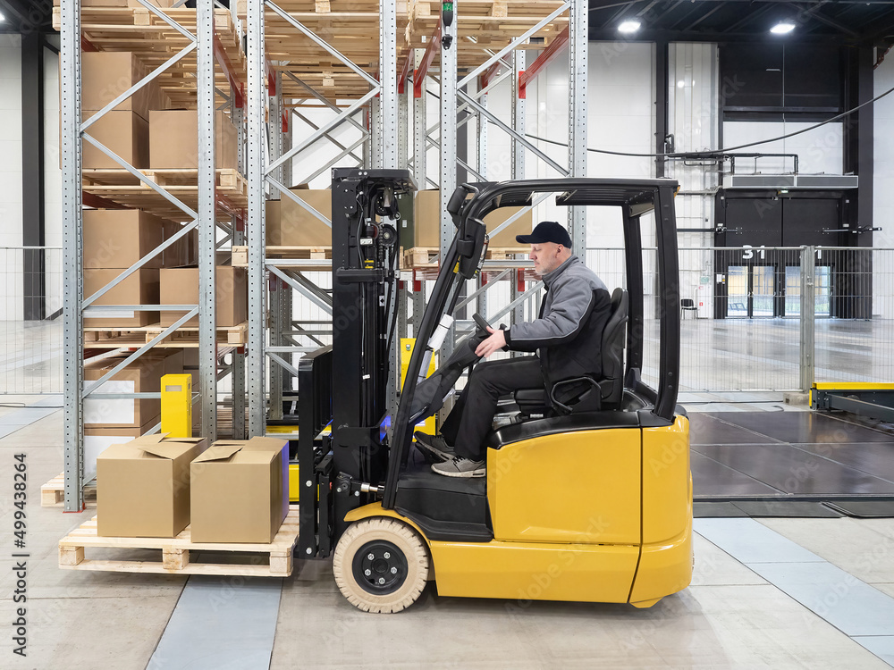 driver operates Forklift. Man works in warehouse. Man on forklift with ...