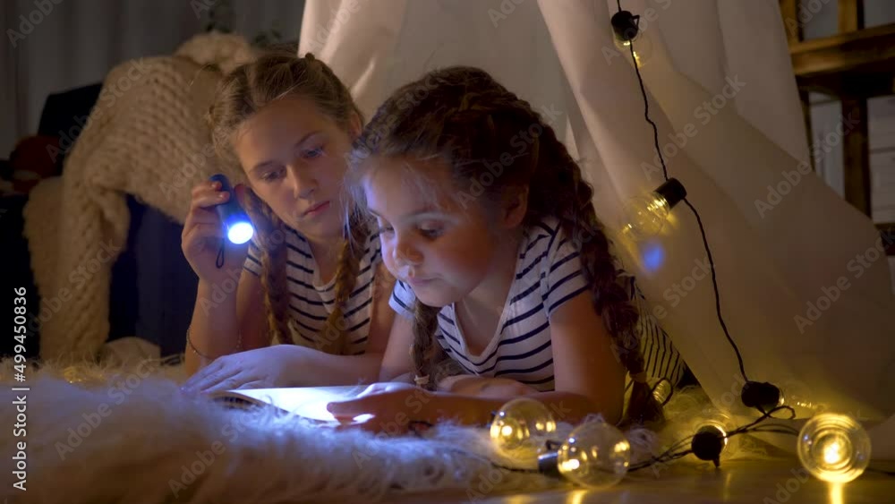 Children read book with flashlight in handmade tent. little kids girls ...