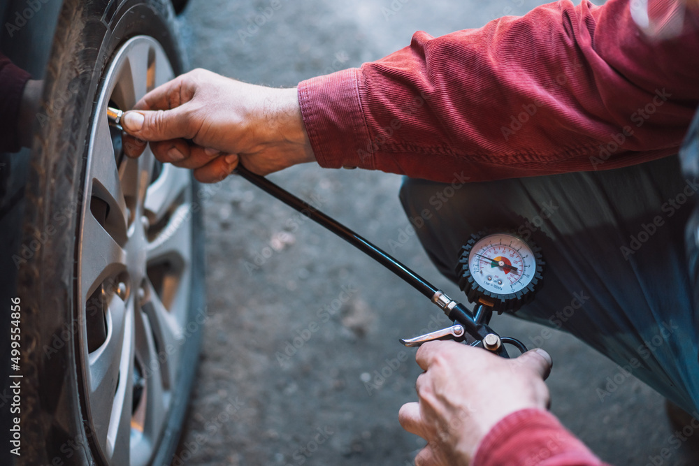 Mechanic checking tire pressure with pneumatic compressor. Stock Photo ...
