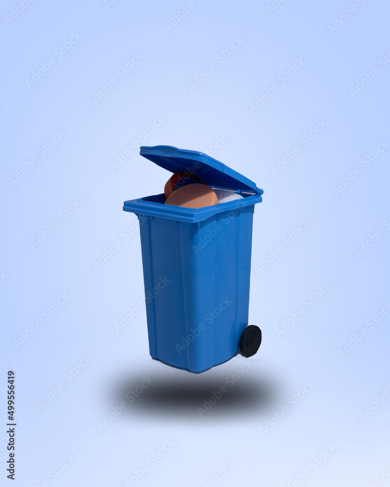 Floating trash can in pastel background. Plastic plugs in garbage can ...
