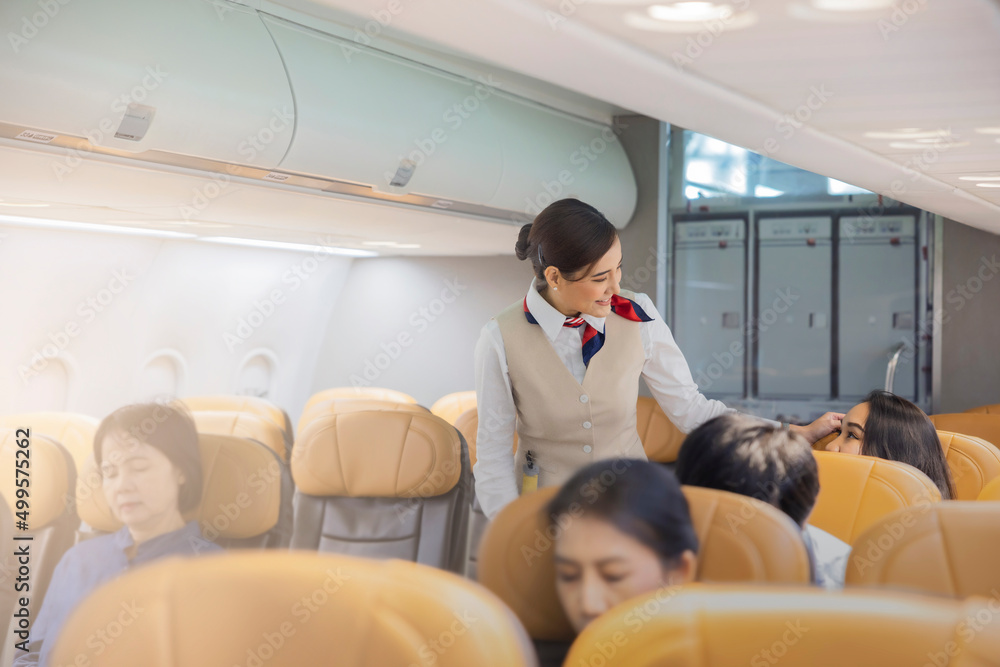 Beautiful female flight attendants checking the passengers on safety ...
