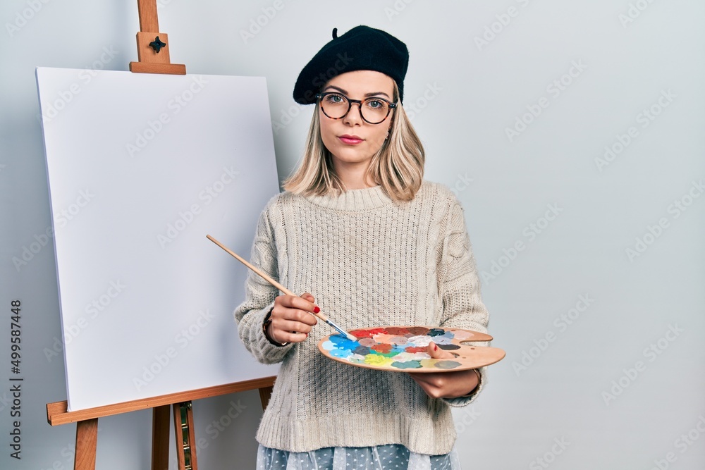 Beautiful caucasian woman drawing with palette on easel stand relaxed ...