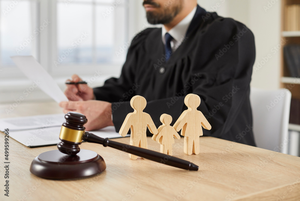 Gavel and little wooden figures of husband, wife and child up close on ...