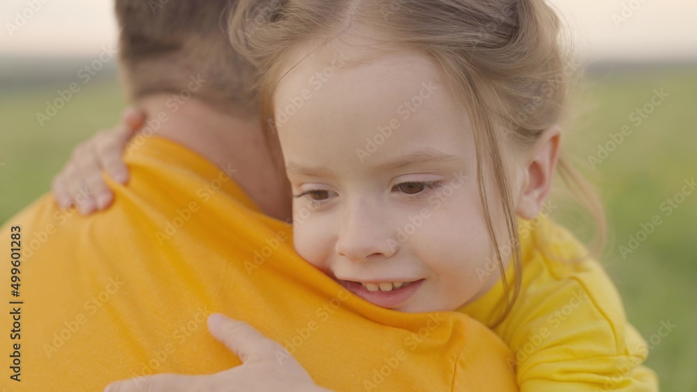 Kid daughter smiles and hugs her dad in park in summer. Close-up. Happy ...