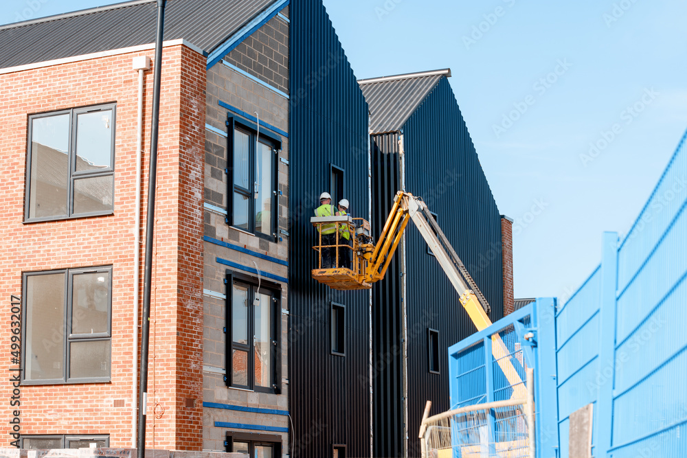 Builders working off Telescopic Boom Lift while fitting insulated ...