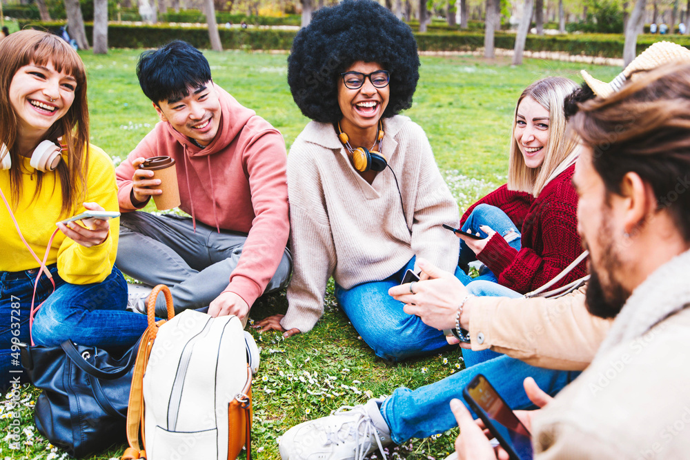 Group of multiracial students sitting in college campus - Young people having fun talking and ...