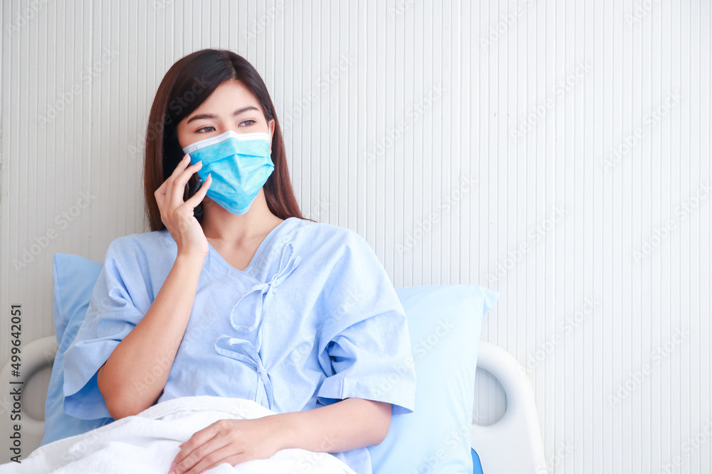Asian female patient wearing mask in hospital patient room She holds ...