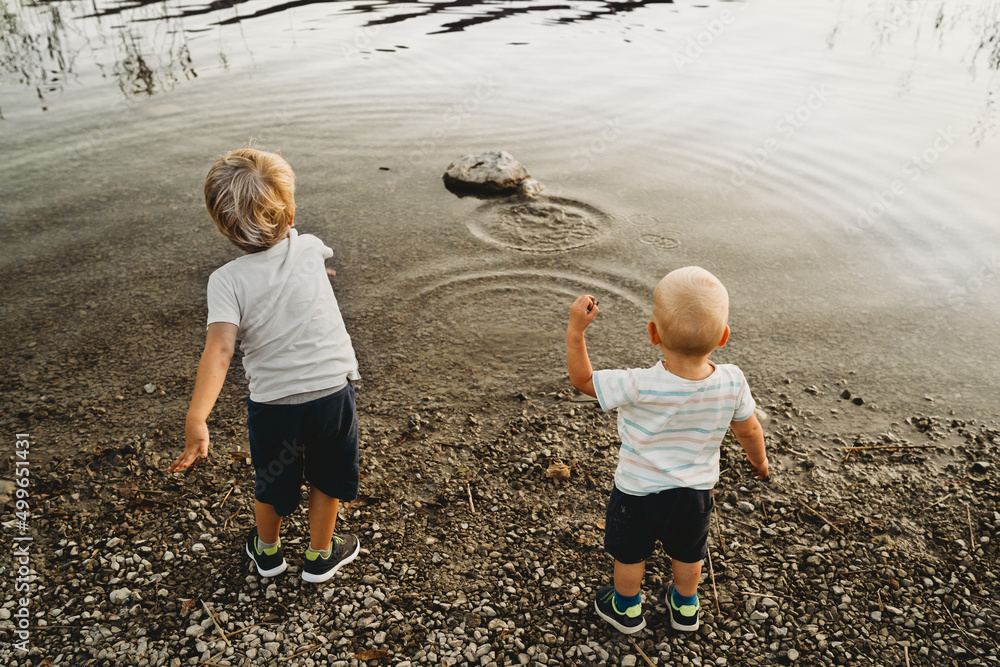 Back view of kids throwing pebbles in water in summer Stock Photo ...