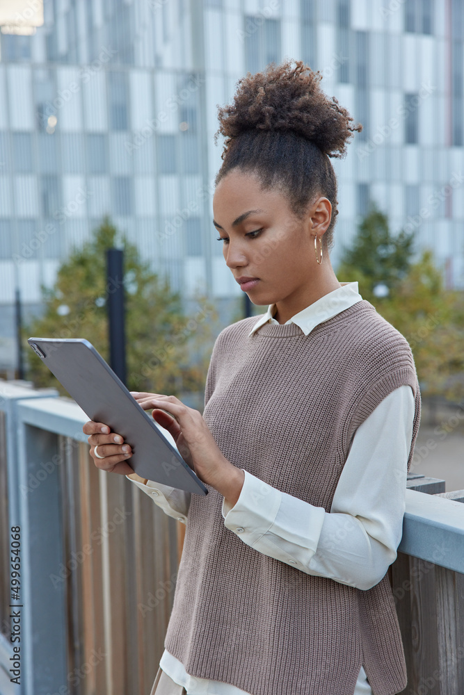 Vertical shot of intelligent student wears neat clothes uses digital ...