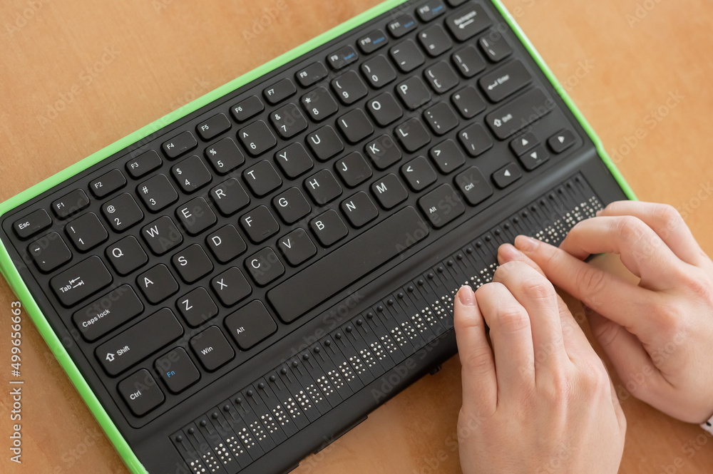 A blind woman uses a computer with a Braille display and a computer ...