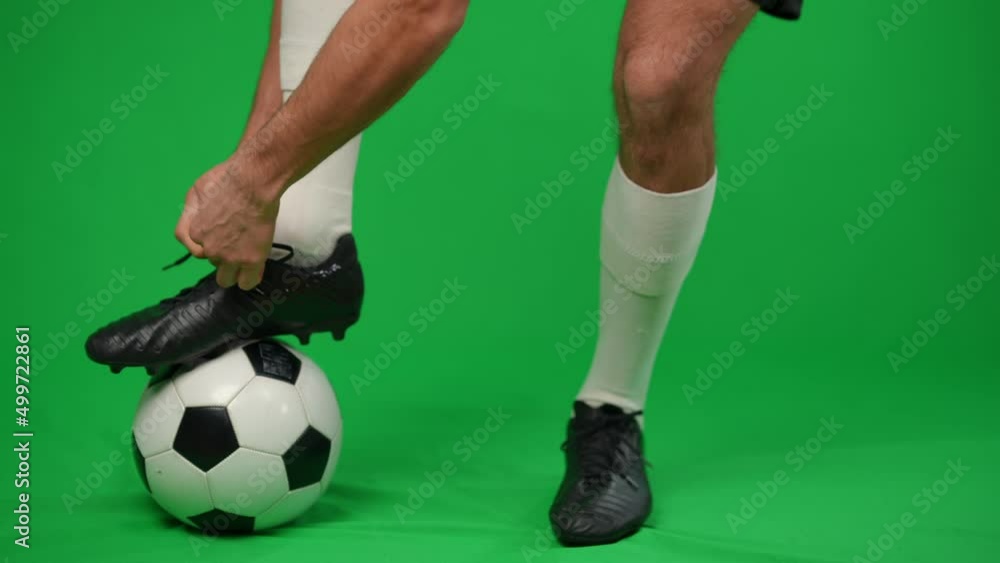 Caucasian sportsman putting foot on soccer ball tying shoelace on ...