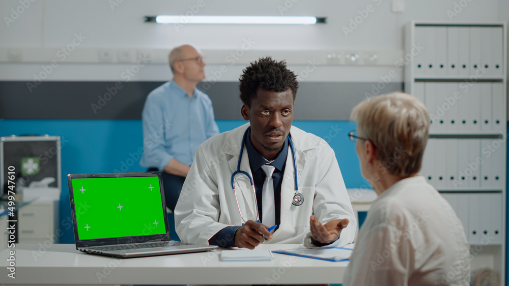 Doctor consulting old patient and having green screen on laptop in ...