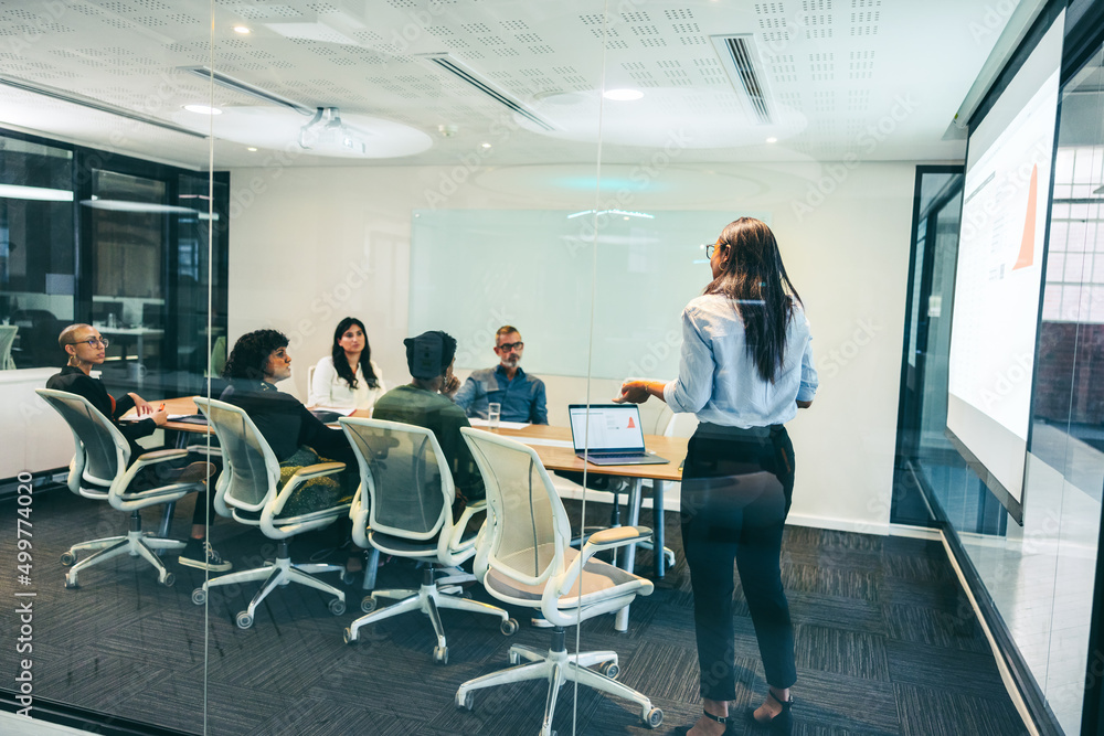 Businesswoman giving a presentation to her colleagues in an office ...