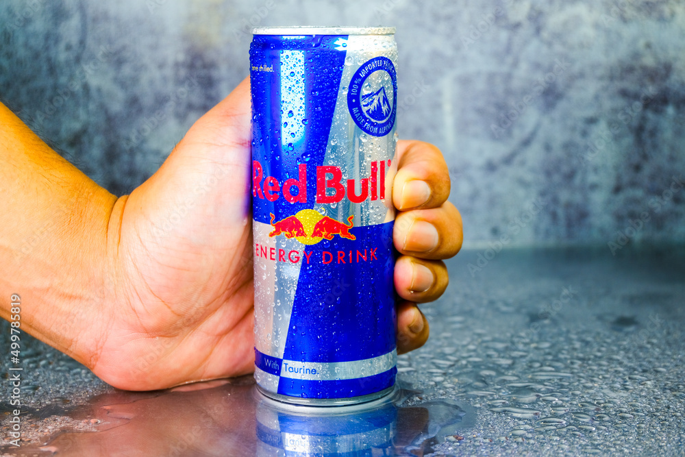 A picture of hand holding cold Red Bull Energy Drink. Red Bull has the ...