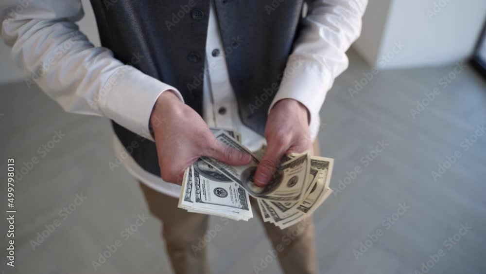 Young employee counts money after getting salary at work in big company ...