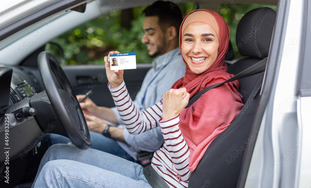 Glad muslim woman in hijab show driving license and fist in open door ...