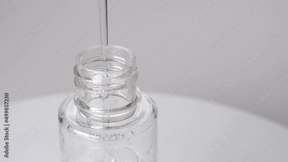 Close-up of a bottle and pouring transparent liquid. Flow of the gel ...