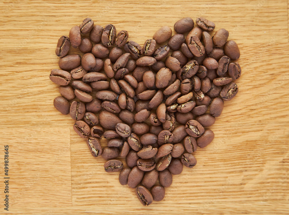 Black coffee beans seed in heart shape on brown wooden table, dark ...