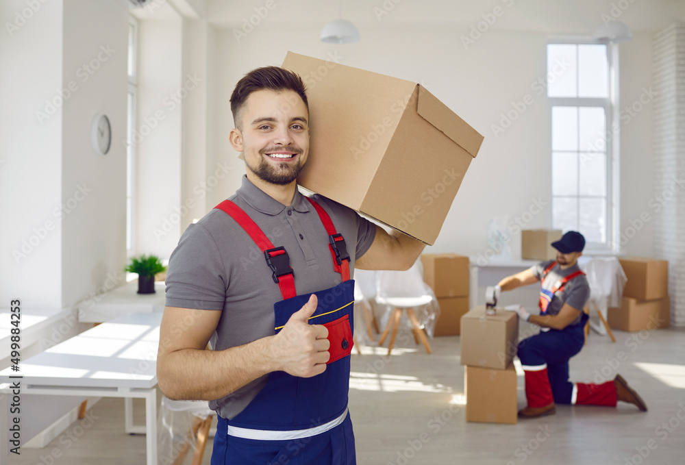 Smiling male worker of moving and delivery company holding cardboard ...
