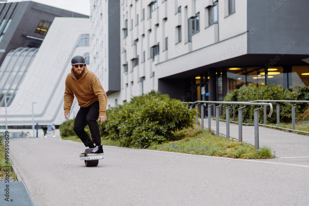 Young man in a helmet rides an electric skateboard. Onewheel rider in ...
