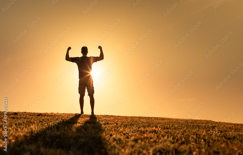Strong, fit, healthy young man silhouette flexing his arms up to the ...