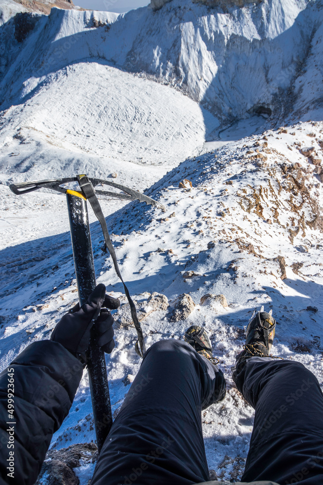 Horizontal picture of mountaineer holding an ice ax and using crampons ...