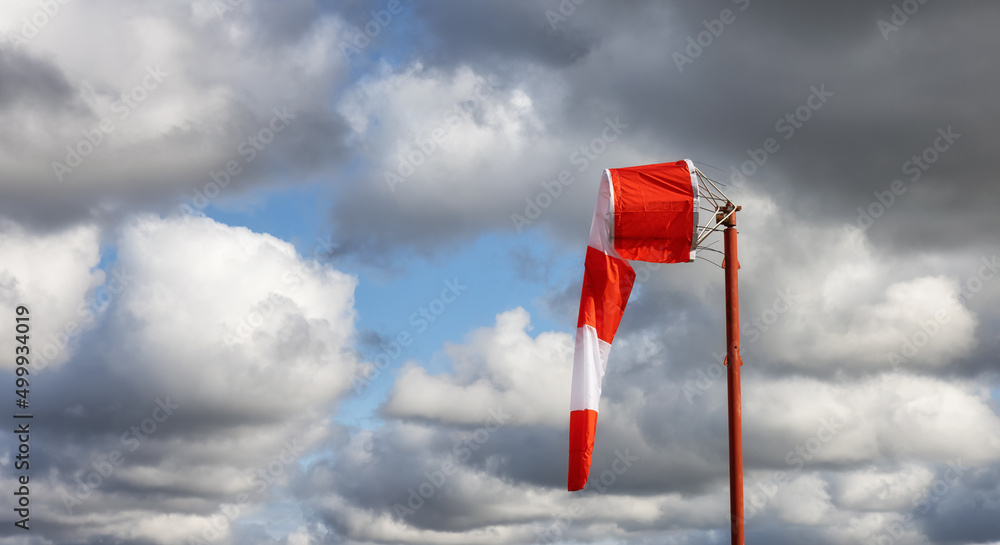 Windsock at an airport with a cloudy sunny sky in background. Light ...