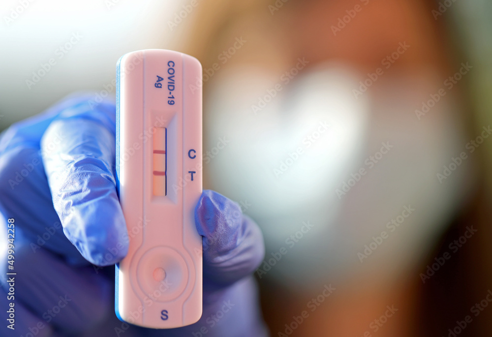 blue glove that holds the rapid test with two lines indicating the ...