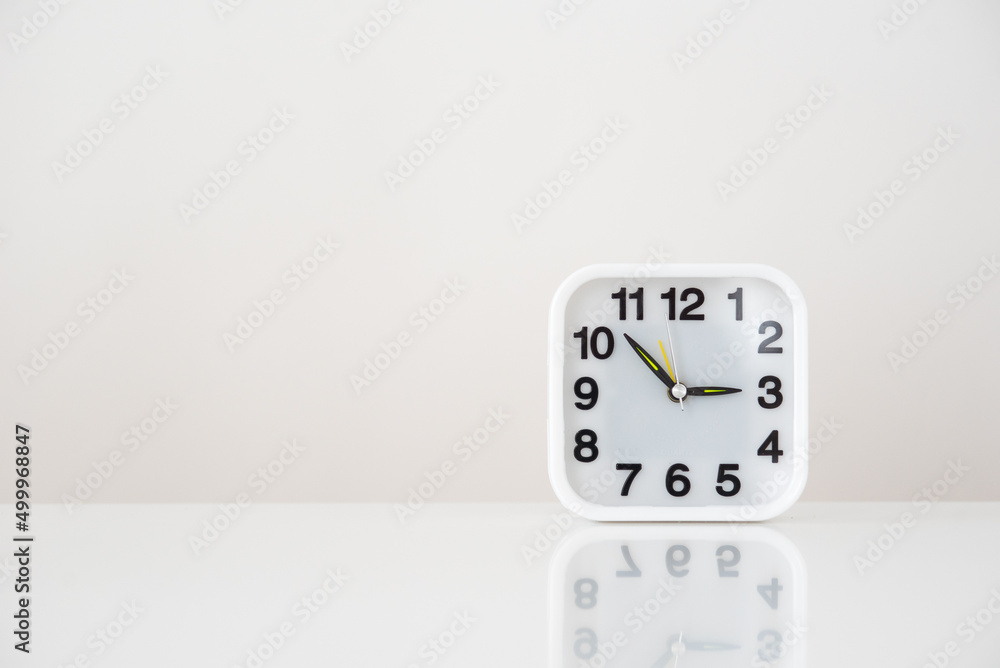 there is a square white clock with black numbers and arrows on a white ...
