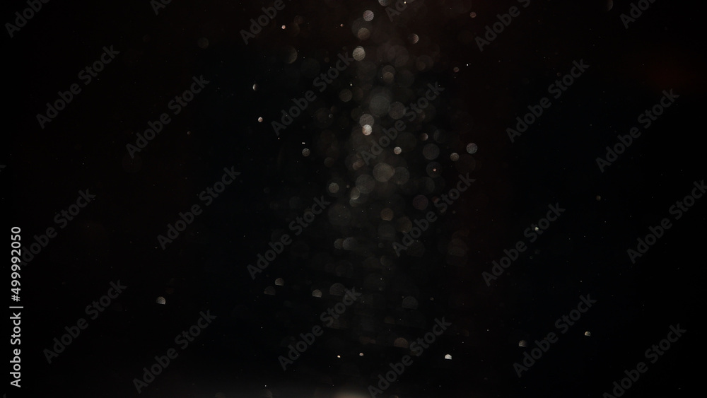 Shot of real dust particles floating in the air on the dark background ...