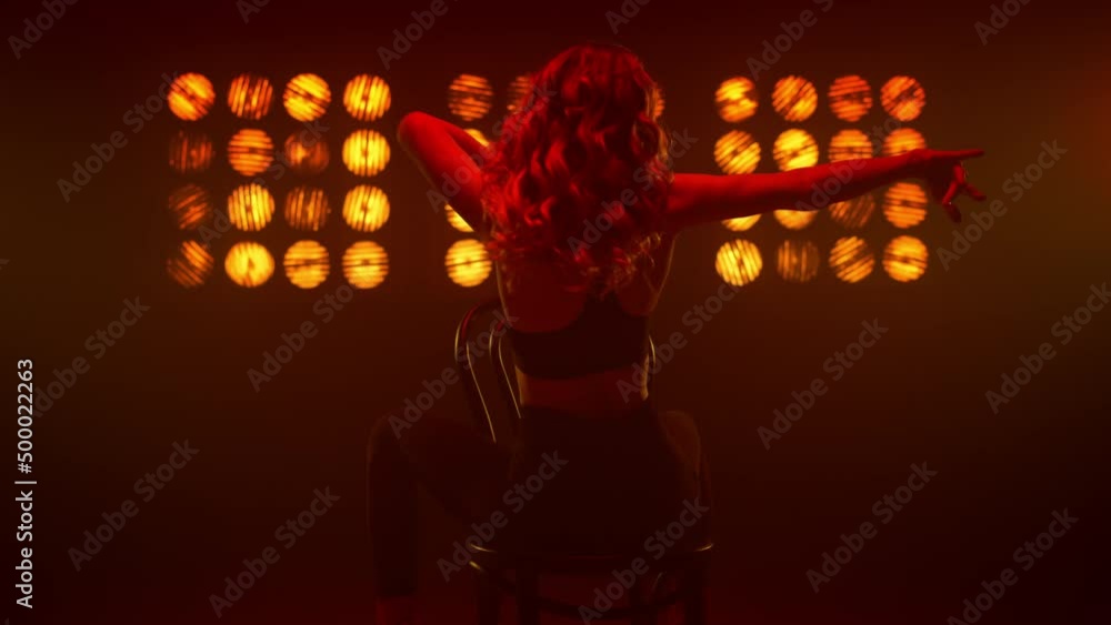 Woman dancing sitting backwards on chair nightclub. Blonde making ...